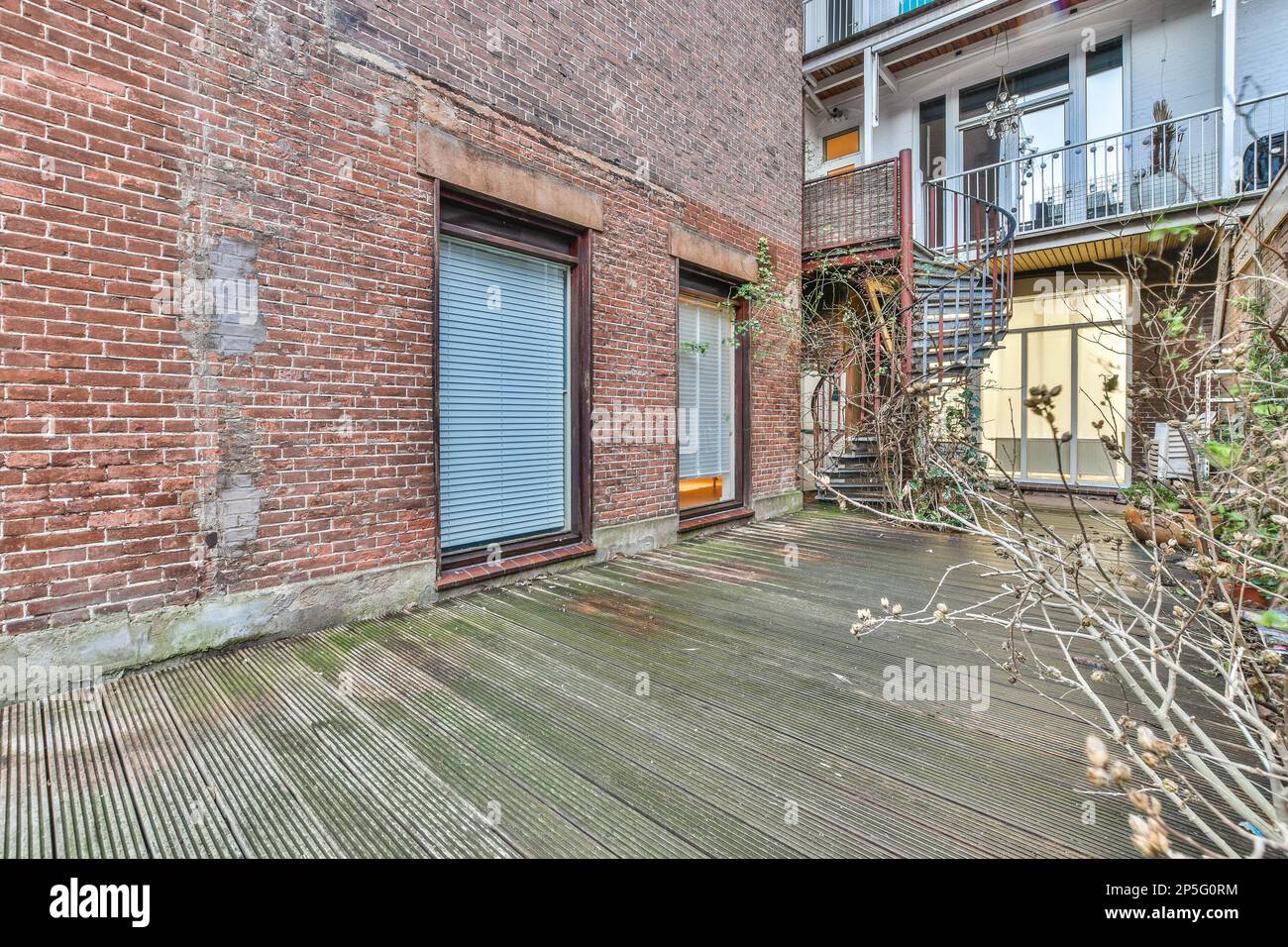 an outdoor area with brick walls and wooden flooring, surrounded by ...