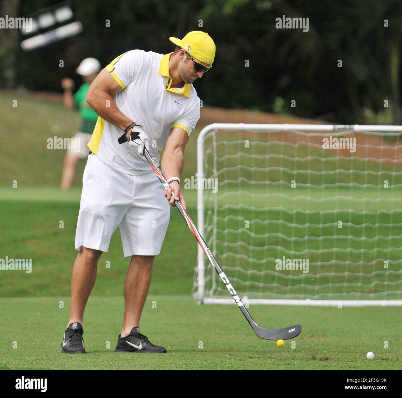 Tim Tebow uses a hockey stick to hit balls on the tee of hole #7 during ...