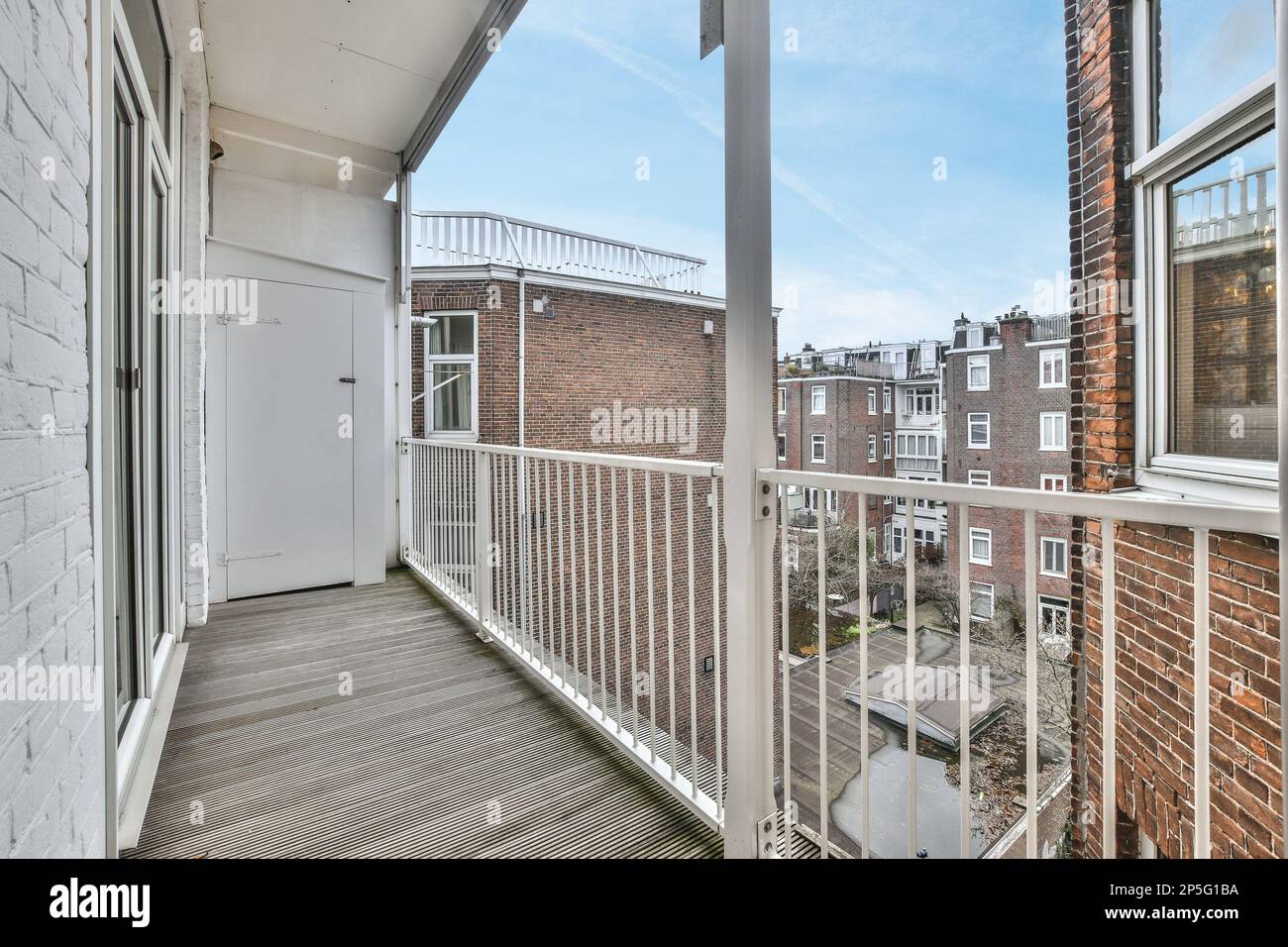 a balcony with white railings and brick buildings in the background, as ...