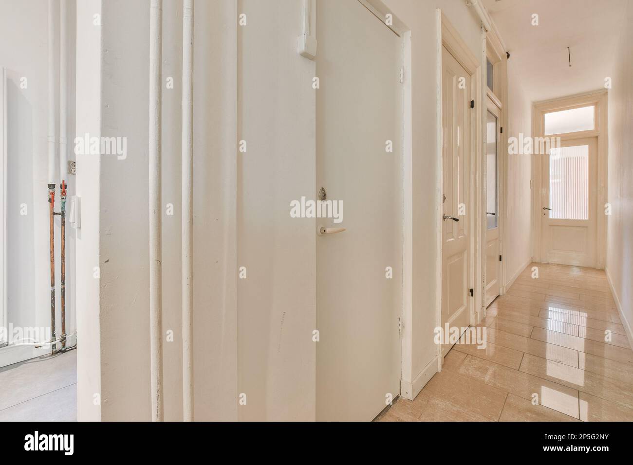 an empty hallway with white walls and door handles on the doors are ...