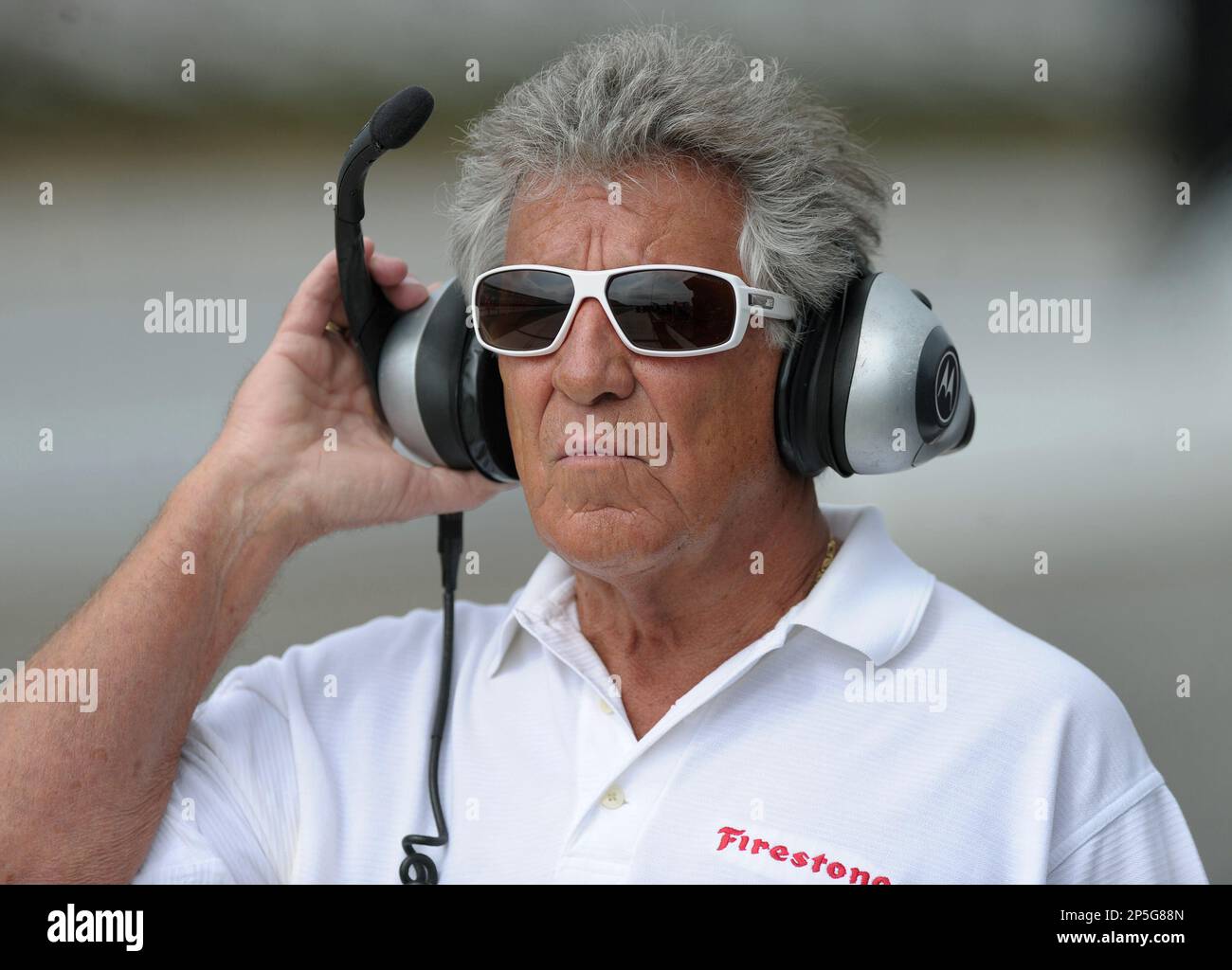 Racing legend Mario Andretti wears a headset as he monitors the car of ...