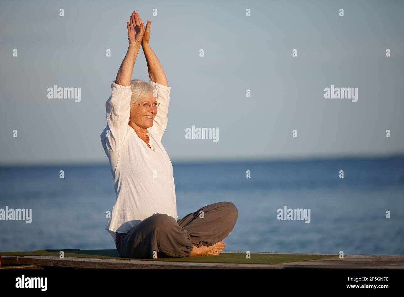 Yoga beside the sea. an attractive mature woman doing yoga on a pier ...