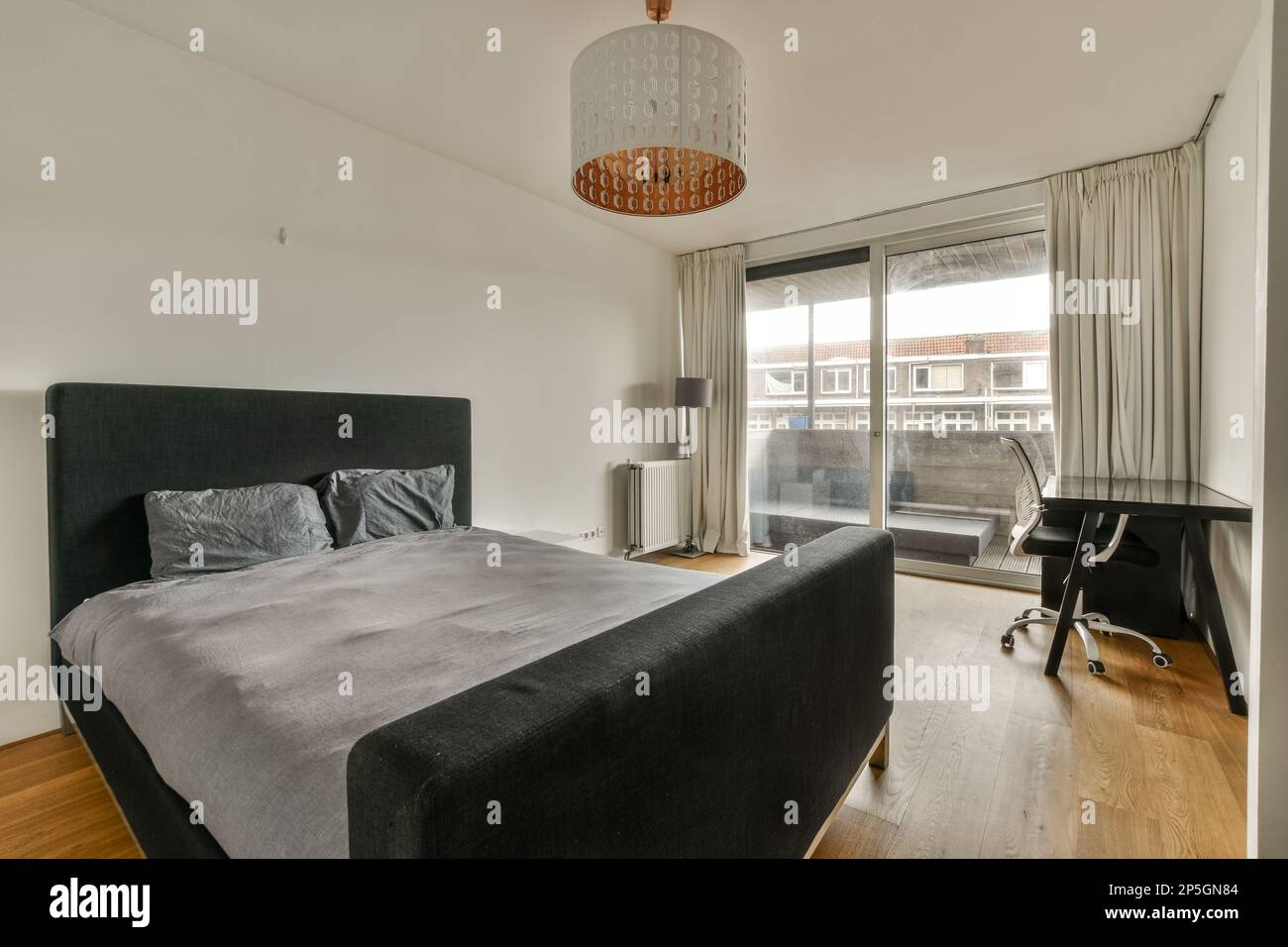 a bedroom with a bed, desk and chair in front of a large window looking ...