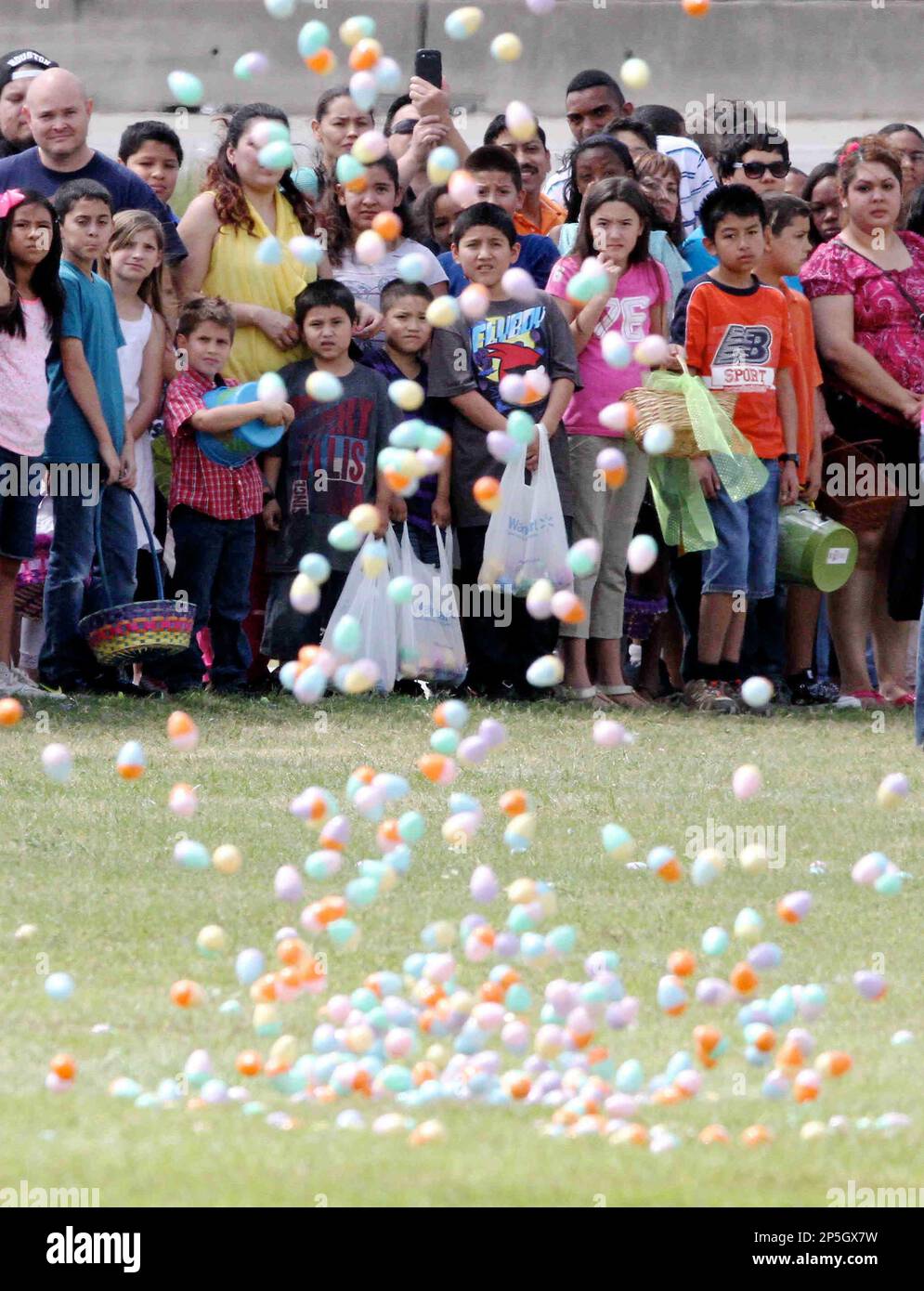 Kids watch as colored Easter eggs drop from a helicopter during an ...