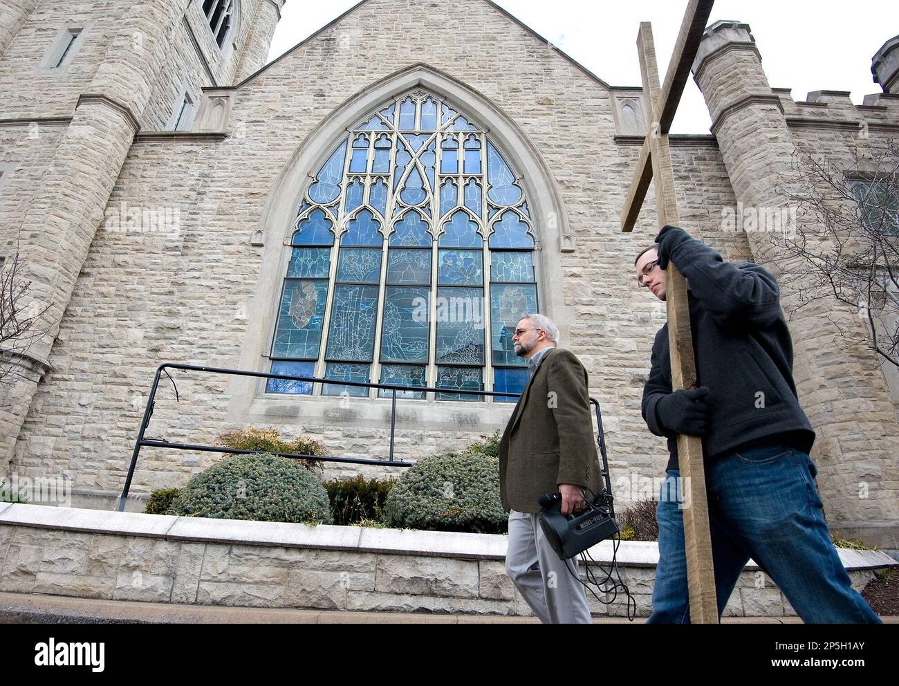 Evan Davis, right, a student at seminary school, walks with the cross ...
