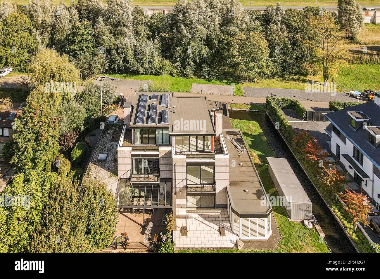 an aerial view of a house with trees and bushes in the fore - image is ...