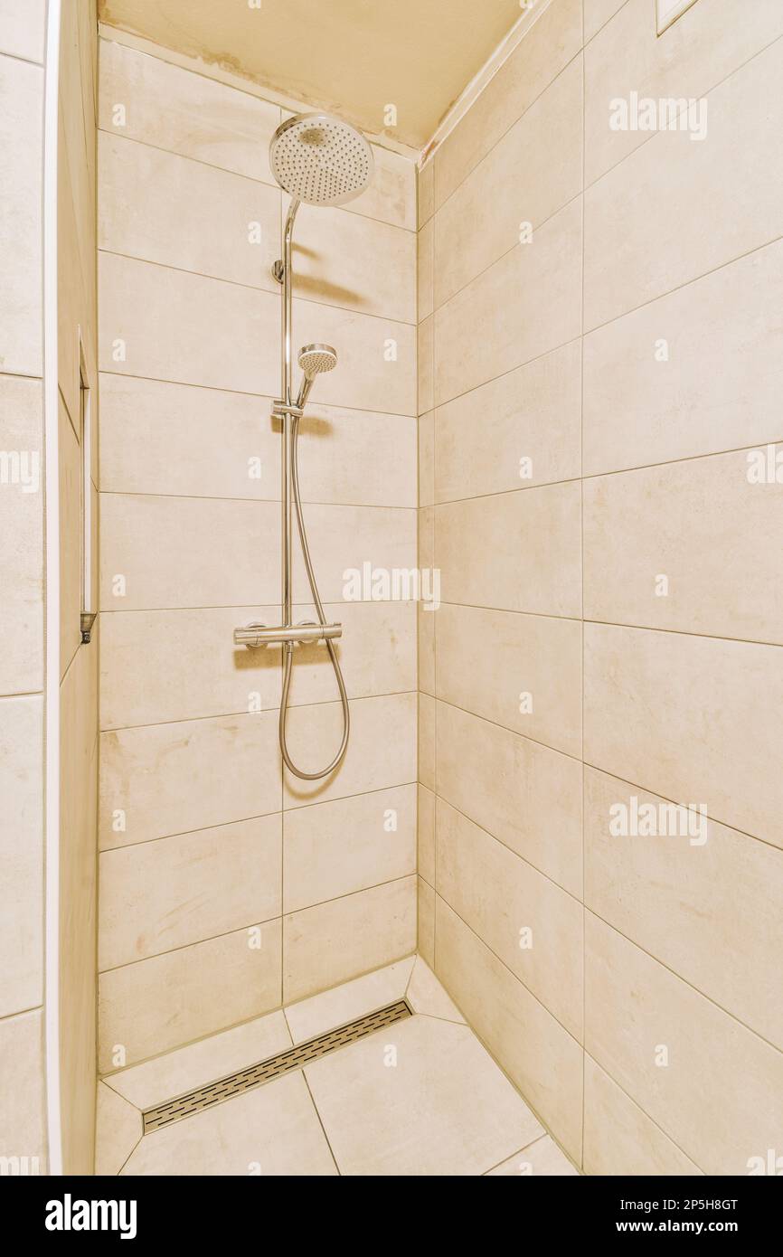 a shower with white tiles on the walls and floor in a small bathroom ...