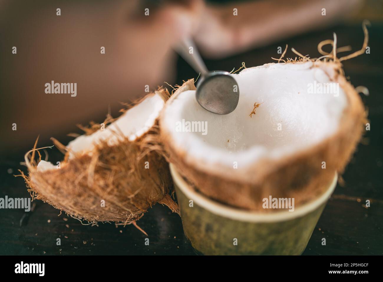 Fresh coconut being open and eaten in restaurant. Woman using spoon to ...