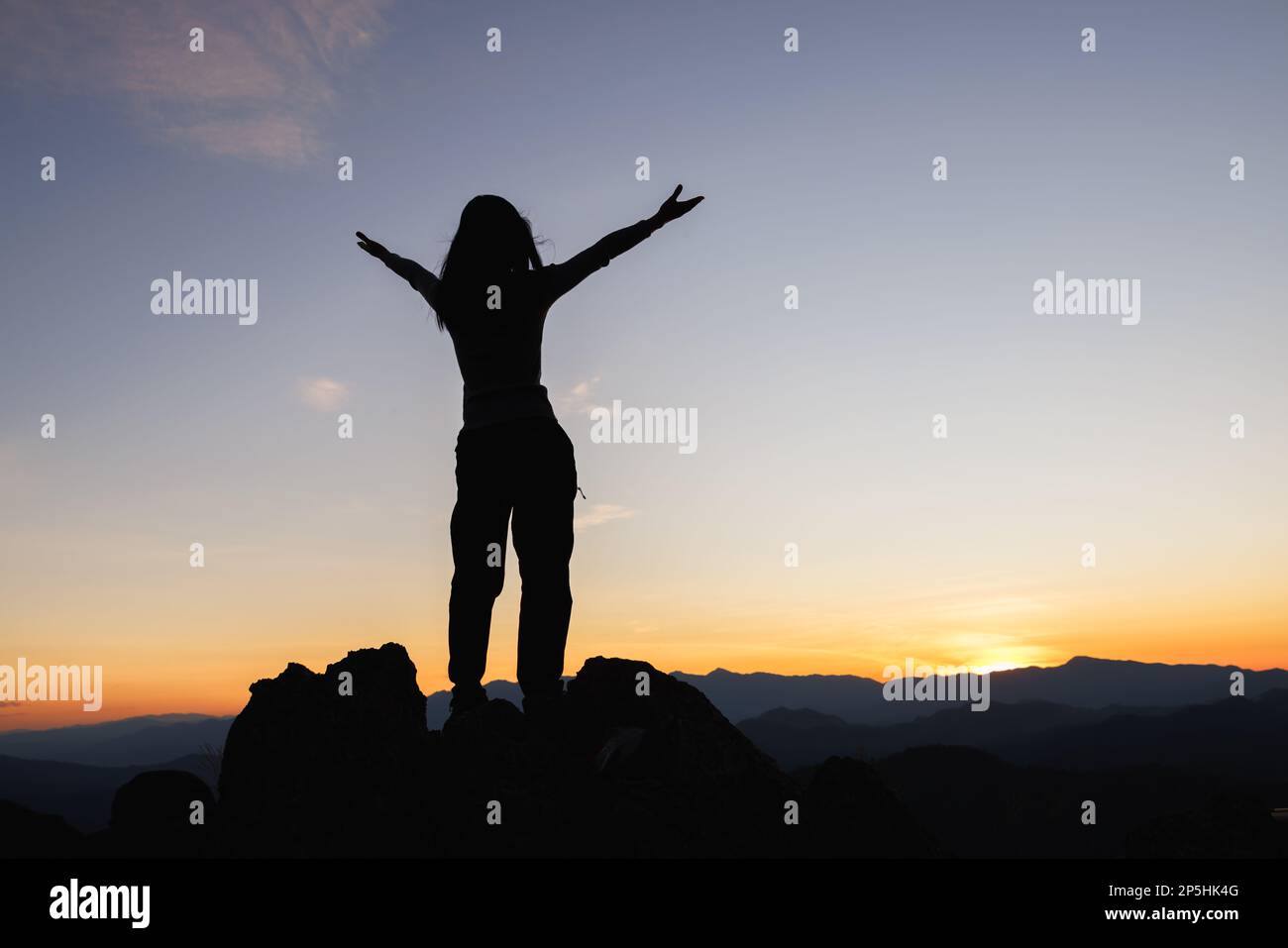 Silhouette of woman on top of the mountain looking to the sun, freedom ...