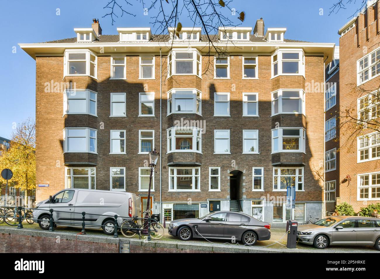 an apartment building with cars parked on the street next to it and two ...