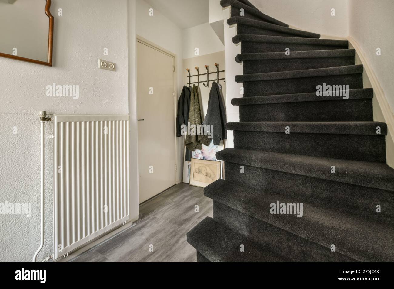 a room with stairs and clothes hanging on the wall in front of an open ...