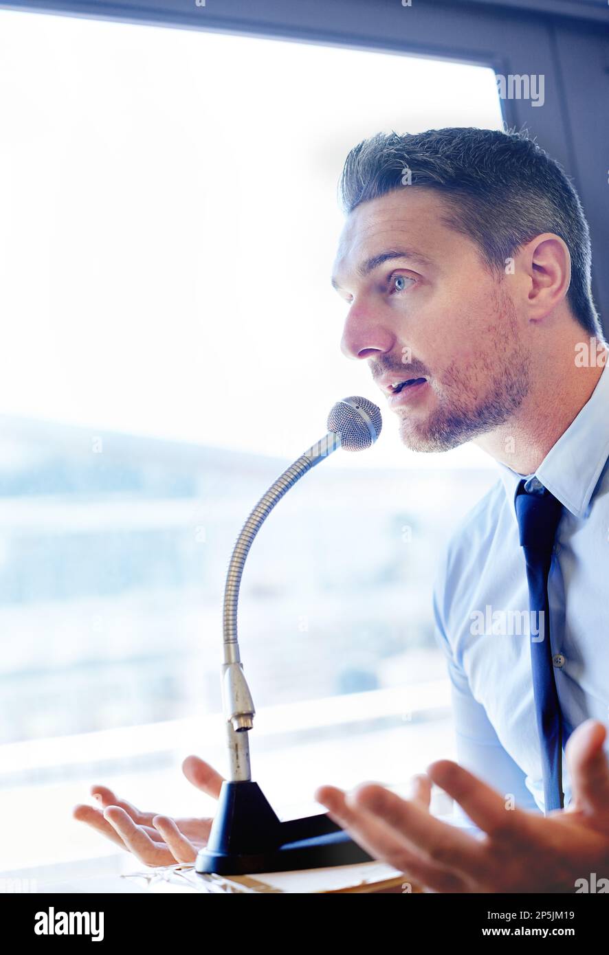 Trying to get his point across...a man in a shirt and tie speaking into ...