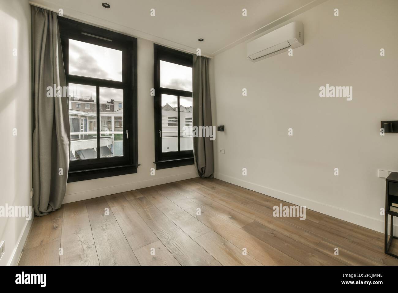 an empty room with wood flooring and two large windows looking out onto ...