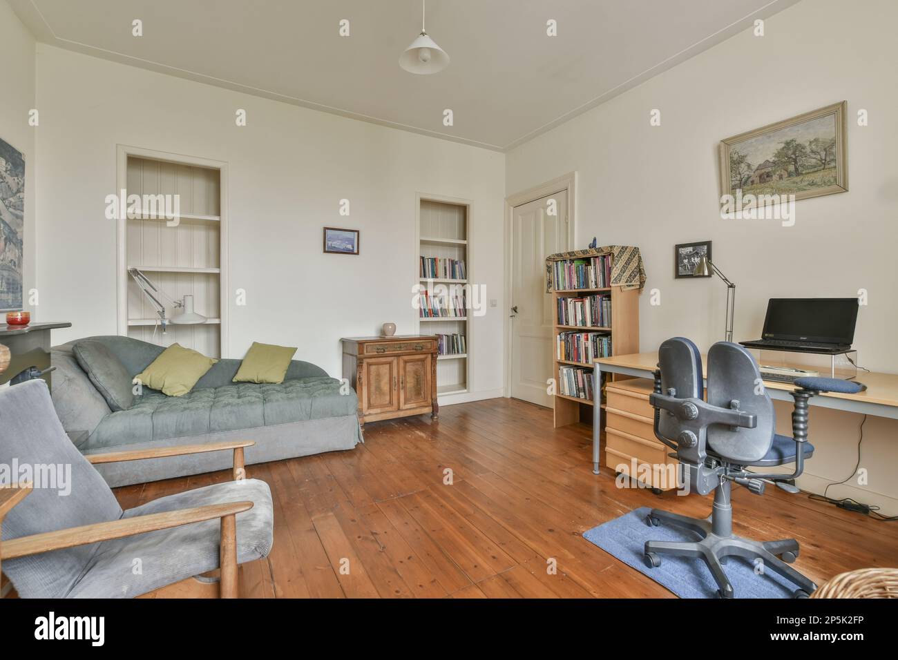 a living room with wood flooring and white walls, there is a computer ...