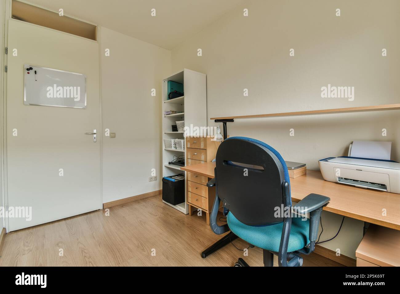 a room with a desk, chair and printer on the wall next to it is an open ...