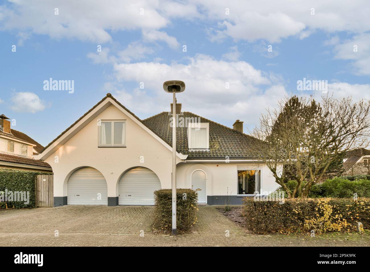 a house that is in the middle of a street with trees and bushes on ...