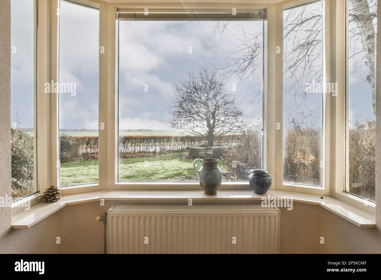 a window with a vase on the windowsill and a view of a field through it ...