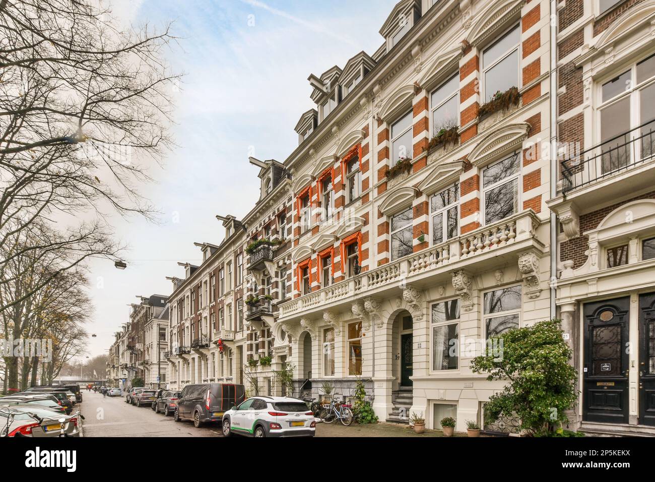 a city street with cars parked on the curbs and trees in front of some ...