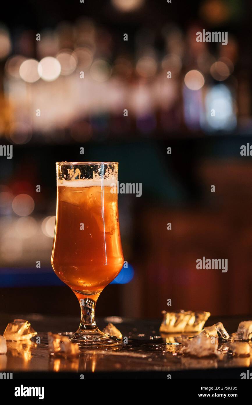 beautiful tulip glass with foamy golden beer ale on bar counter in pub ...