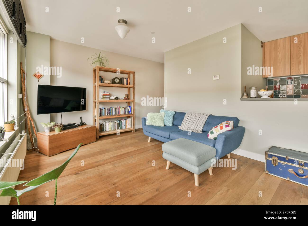 a living room with wood flooring and a blue couch in the center of the ...