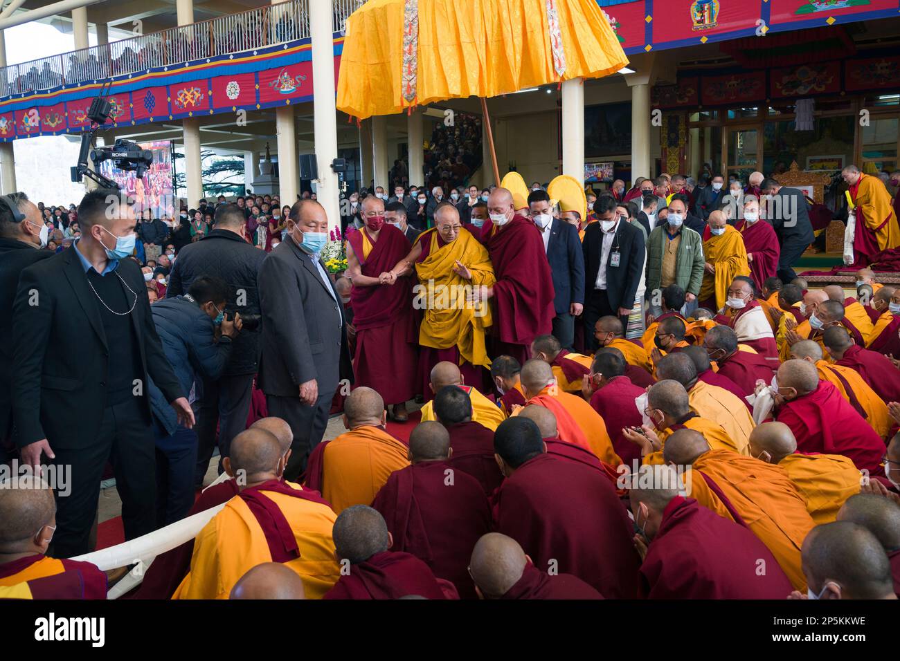 Tibetan spiritual leader the Dalai Lama, in yellow robe, is surrounded ...