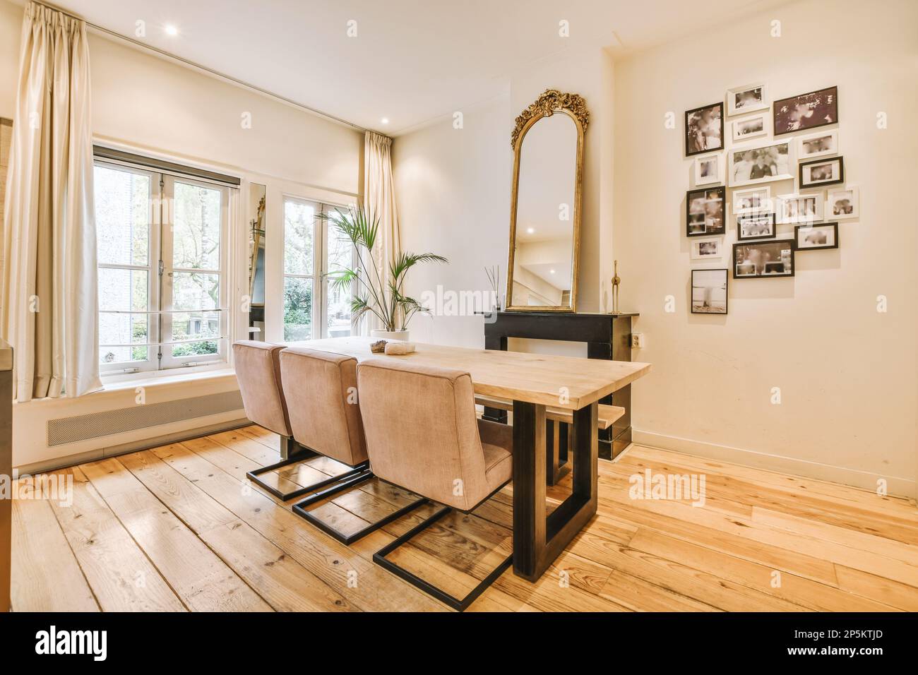 a living room with wood flooring and white walls, two chairs are facing ...