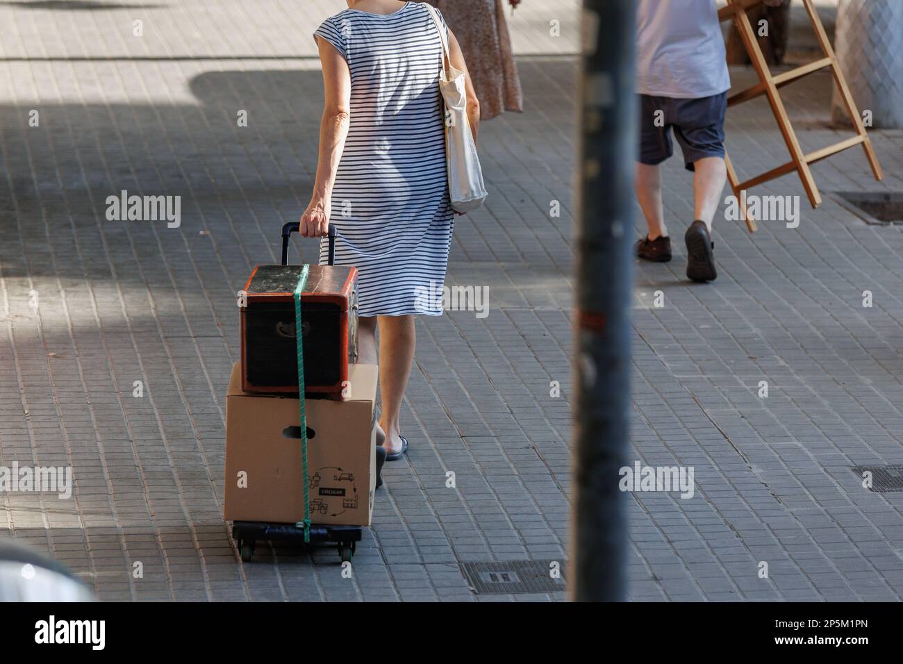Lady Walking on the Sidewalk Dragging a Cart with Boxes on It Stock ...