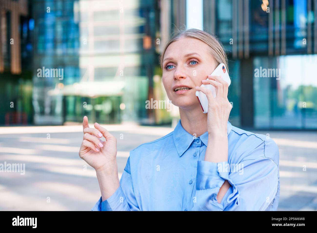Successful female banker using smart phone outdoors while standing near ...