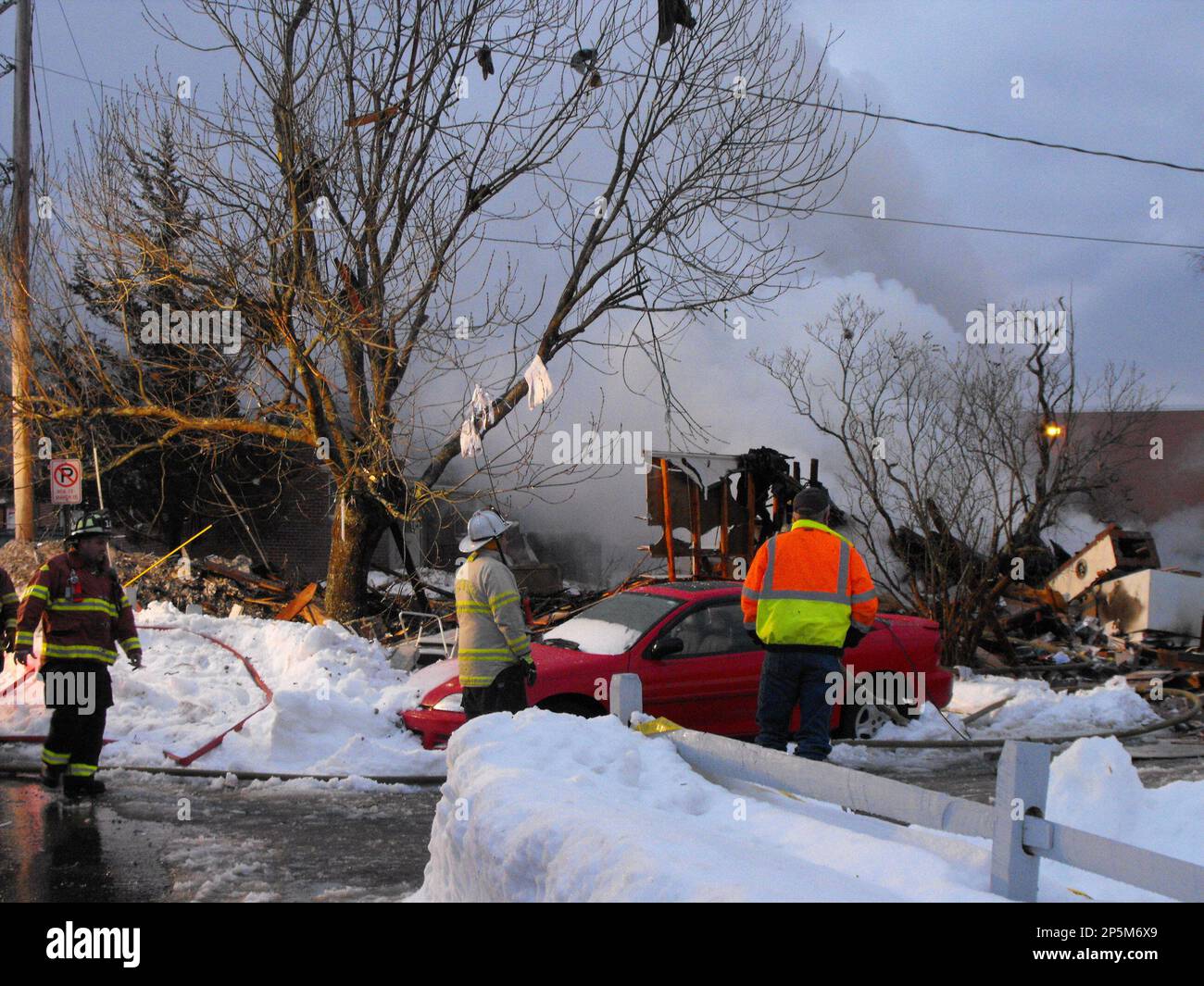 Firefighters survey the remains of a fire after an explosion at a ...