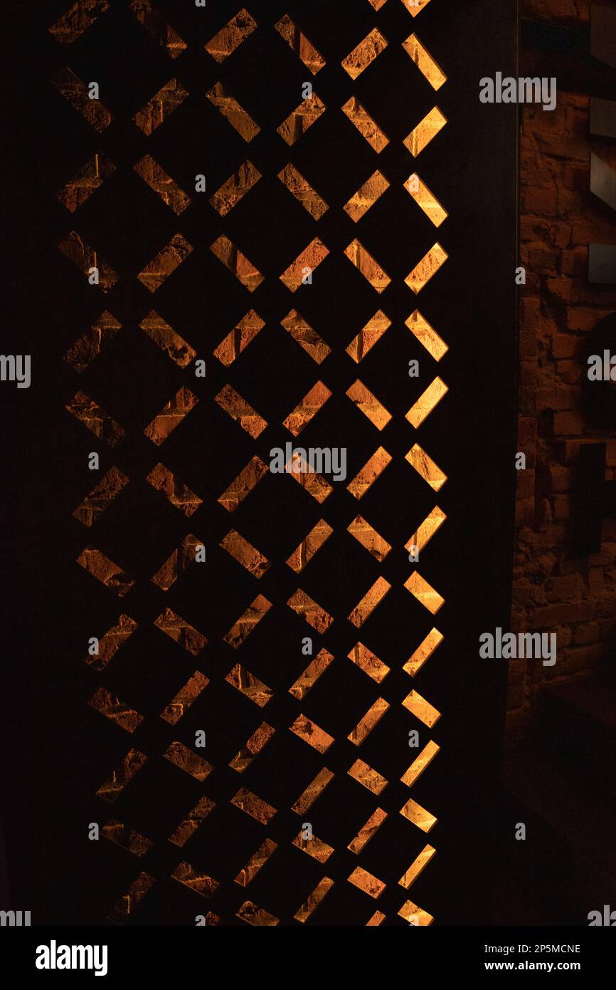 Decorative metal partition with geometric holes, illuminated brick wall ...