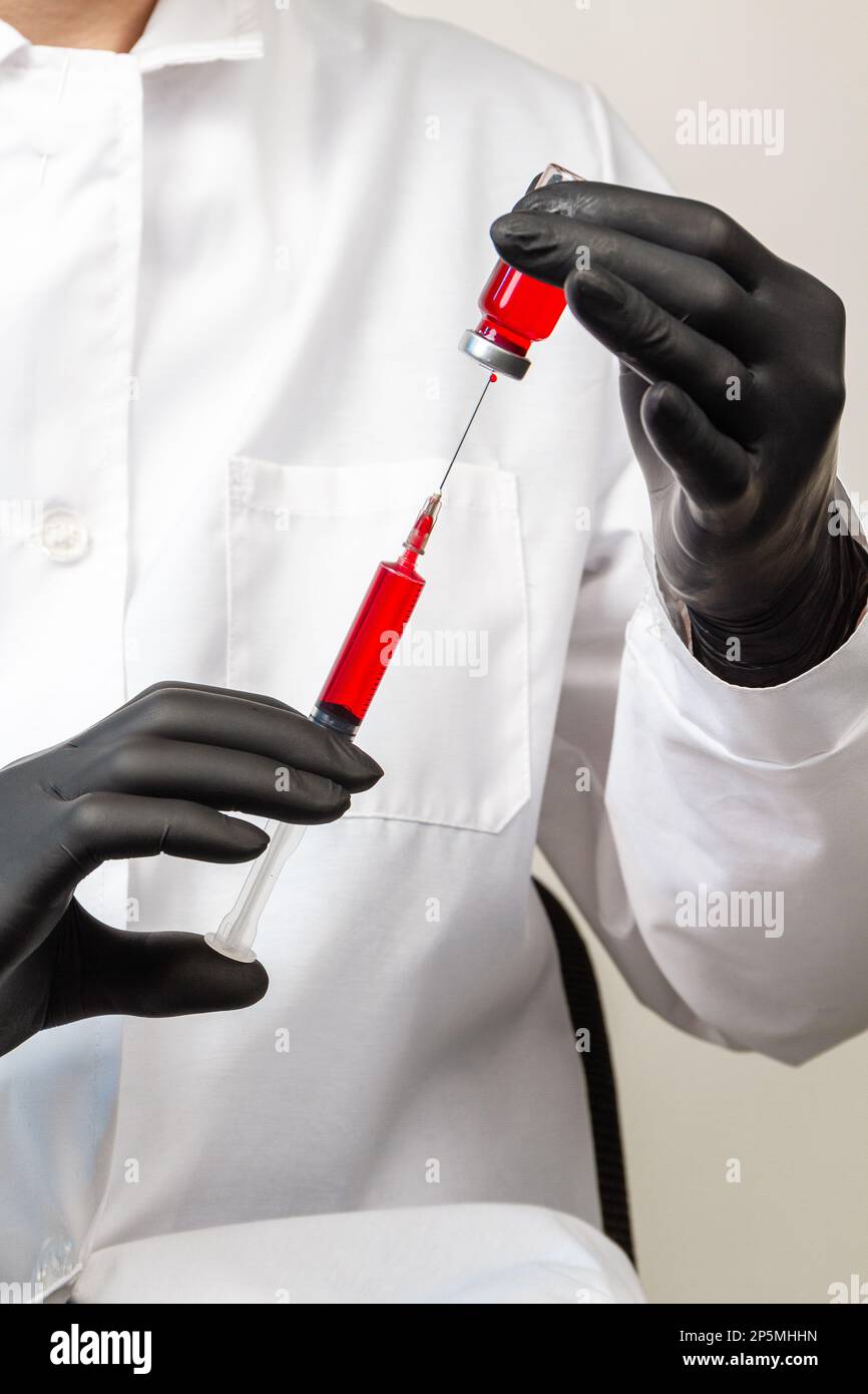 Doctors hands in black gloves filling syringe with medication. Vertical ...