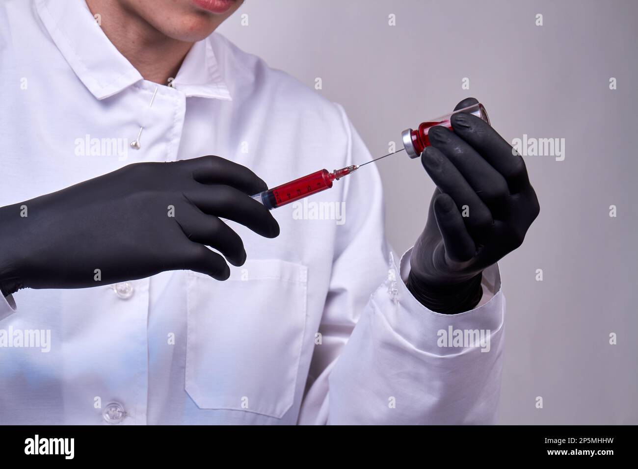 Doctor with black glove filling syringe with medication. Vaccination and immunization Stock ...