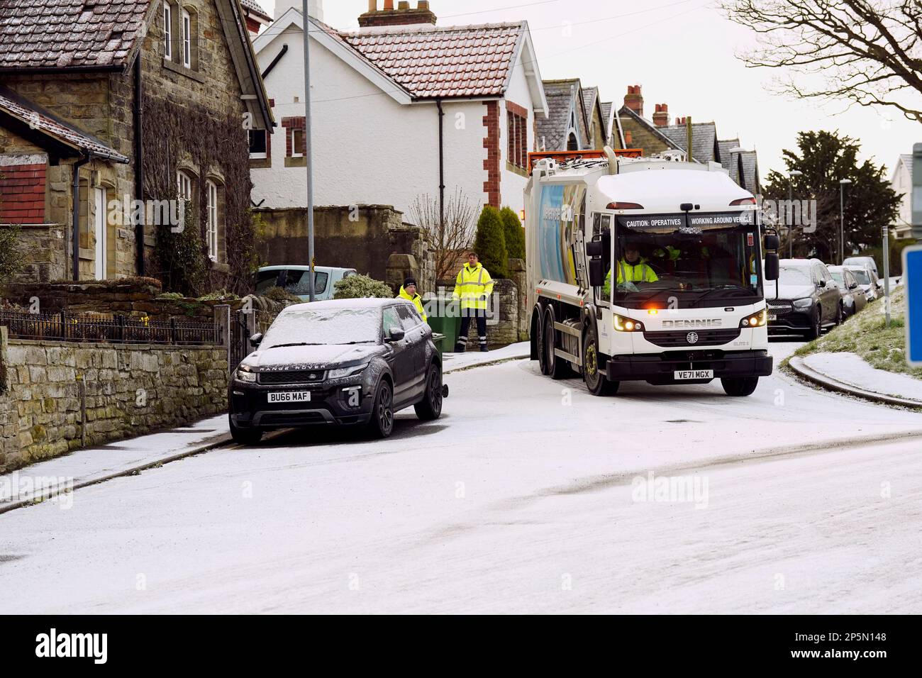 Refuse collectors clears the bin in snowy conditions in Briggswath, North Yorkshire, as weather ...