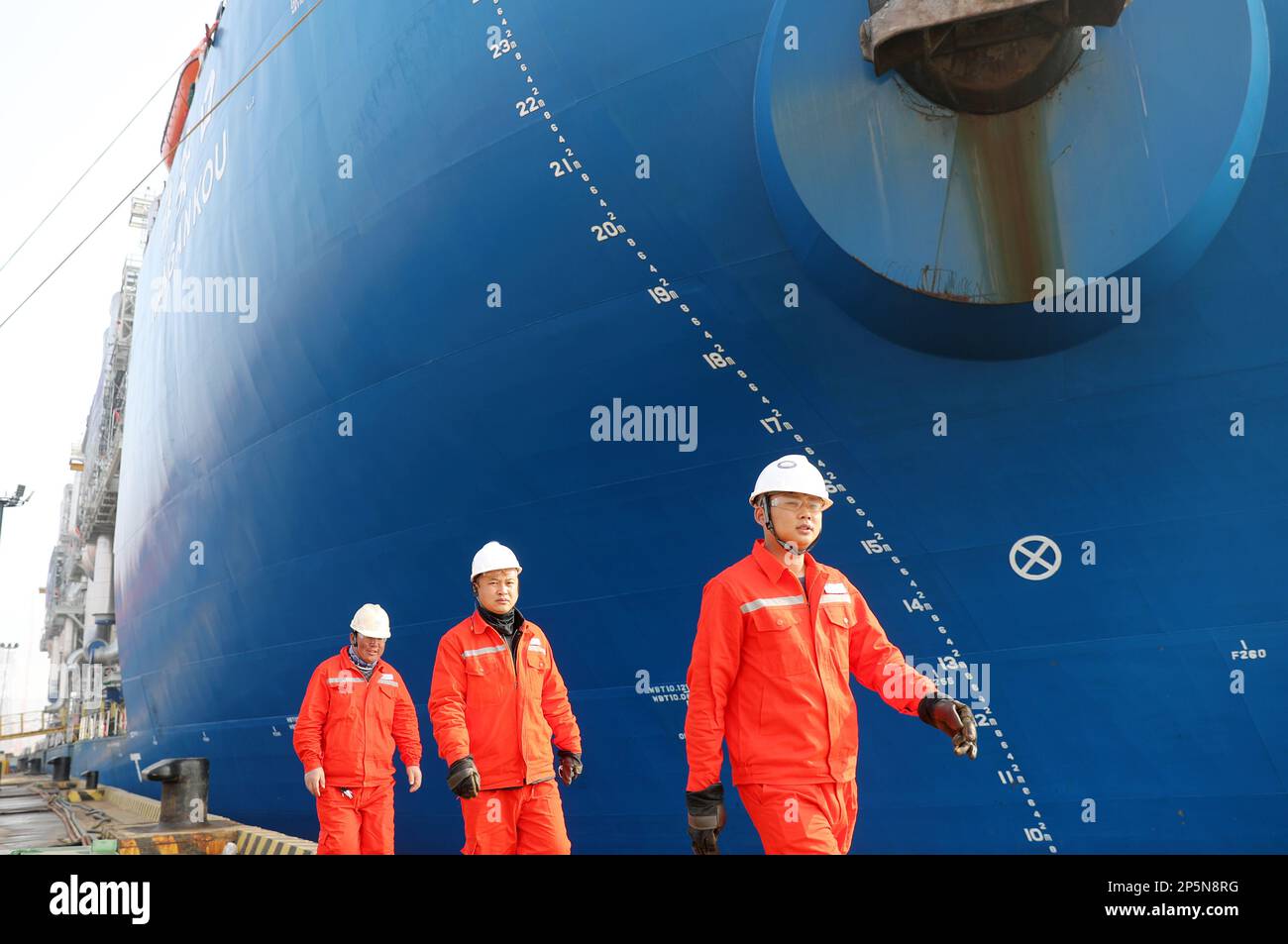 QINGDAO, CHINA - MARCH 7, 2023 - Workers pass the side of an LNG ...