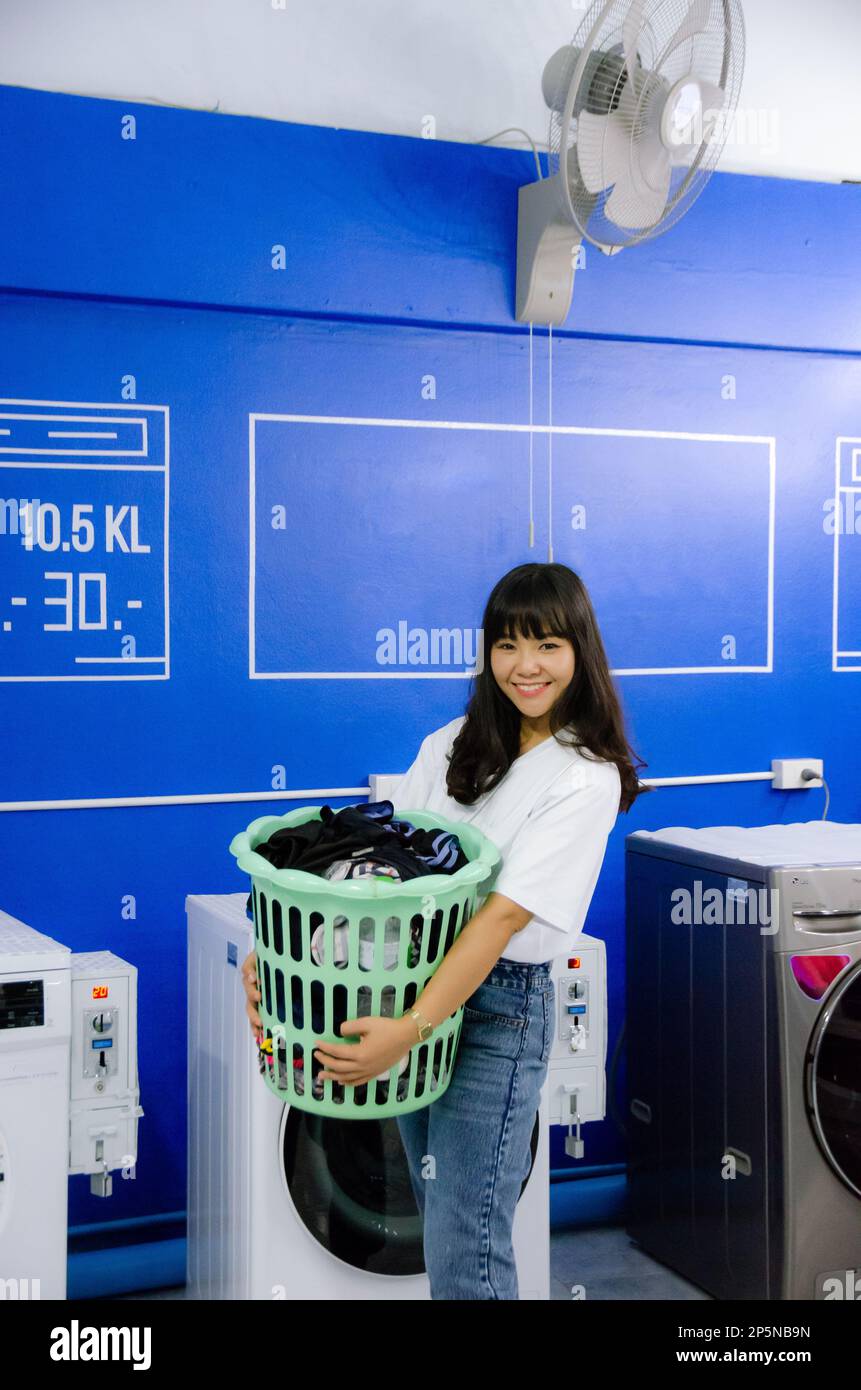 Asian girl is holding basket in laundry shop with smile face Stock Photo - Alamy