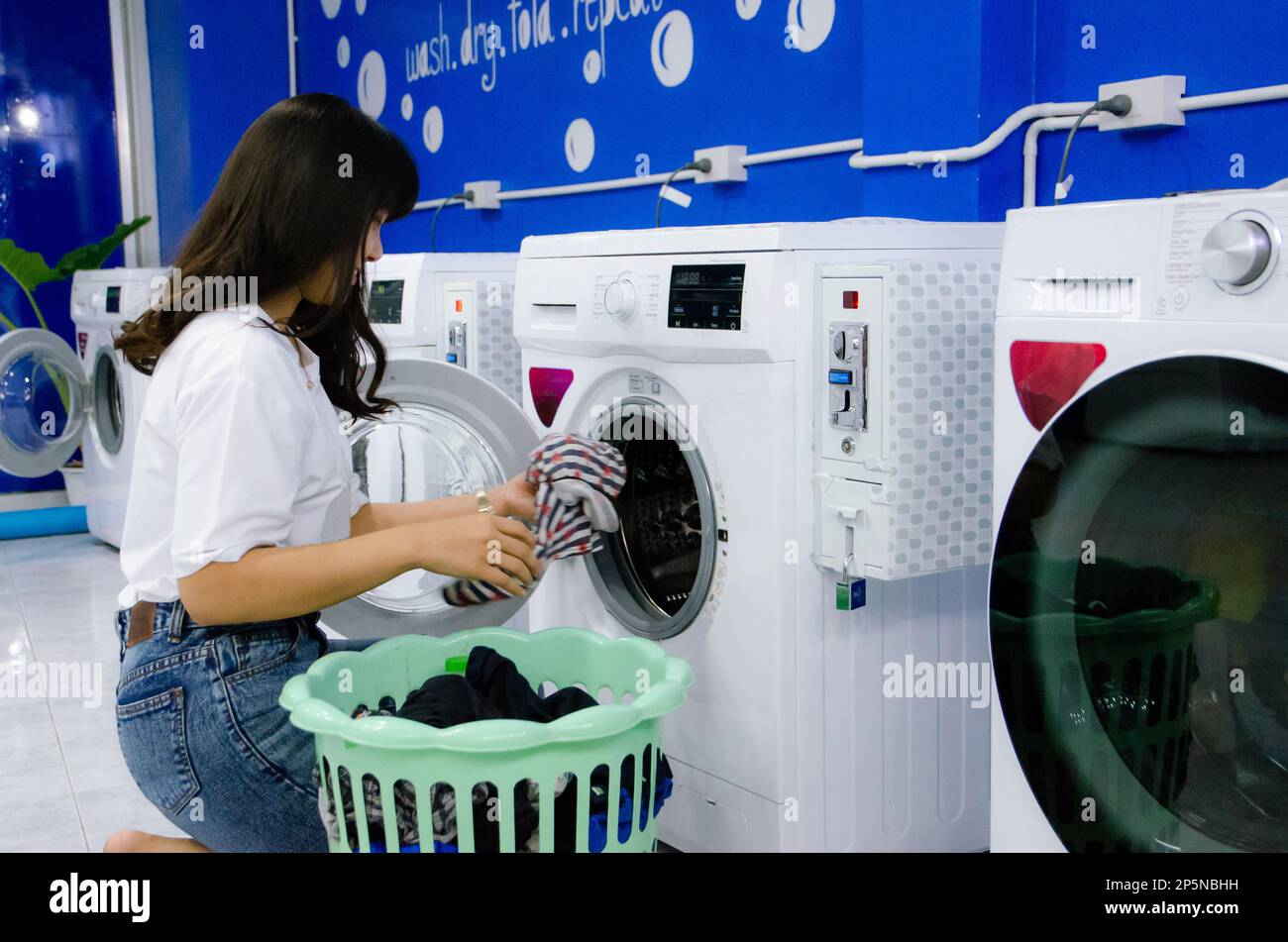 Asian girl is washing cloths by washing machine in laundry shop Stock ...