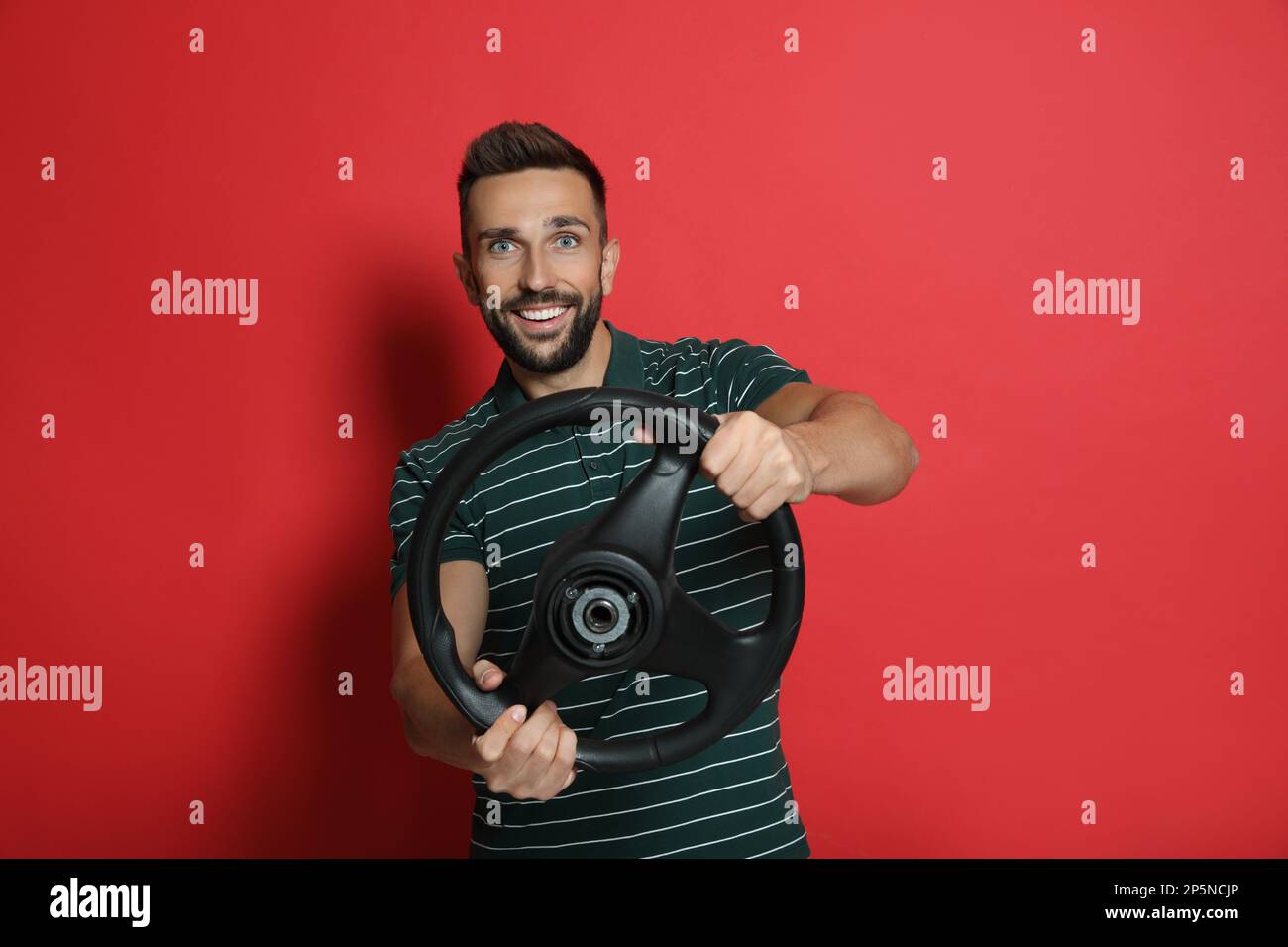 Happy man with steering wheel on red background Stock Photo - Alamy