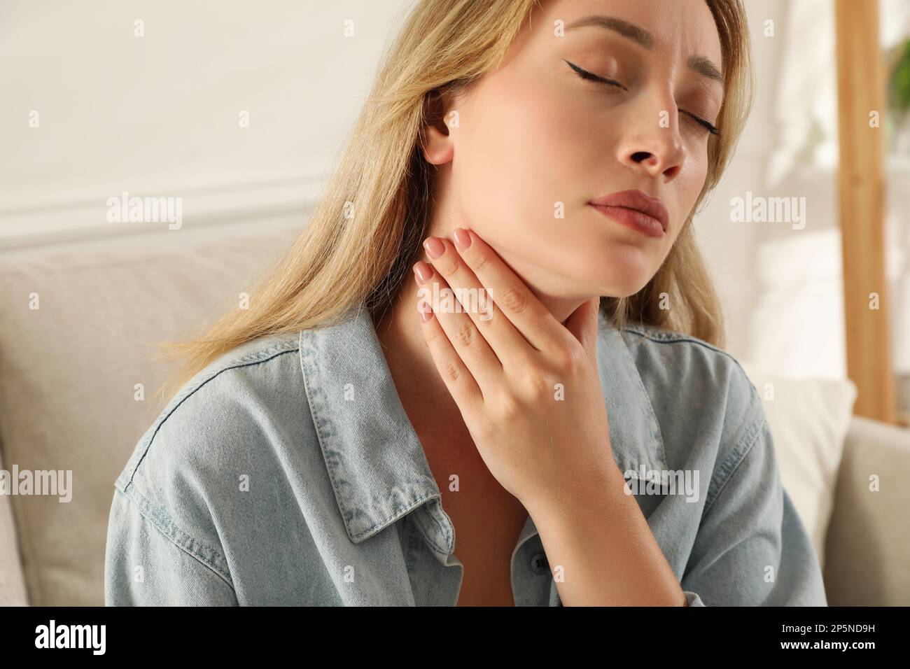 Young woman doing thyroid self examination at home Stock Photo - Alamy
