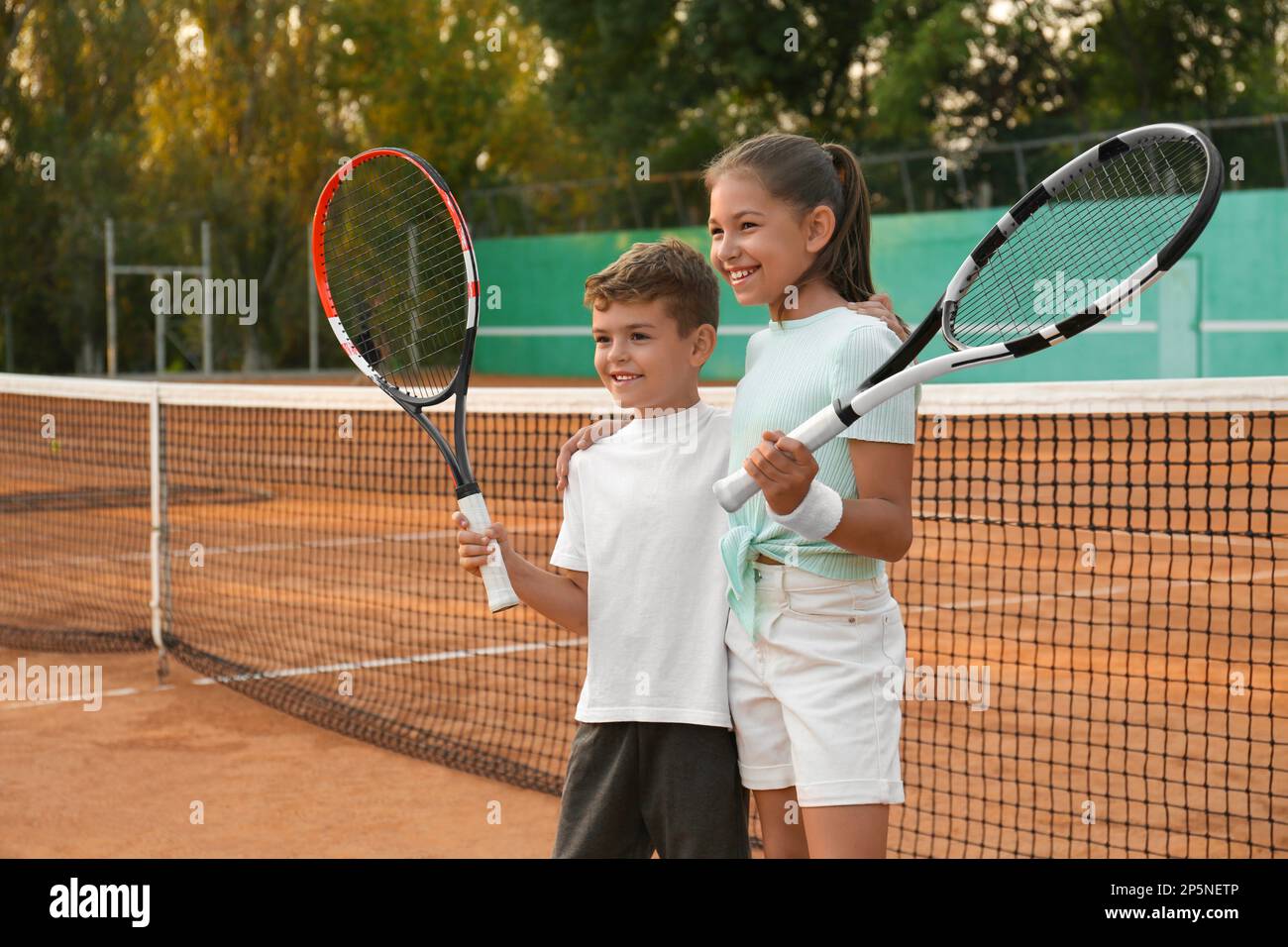 Happy children with tennis rackets on court outdoors Stock Photo - Alamy