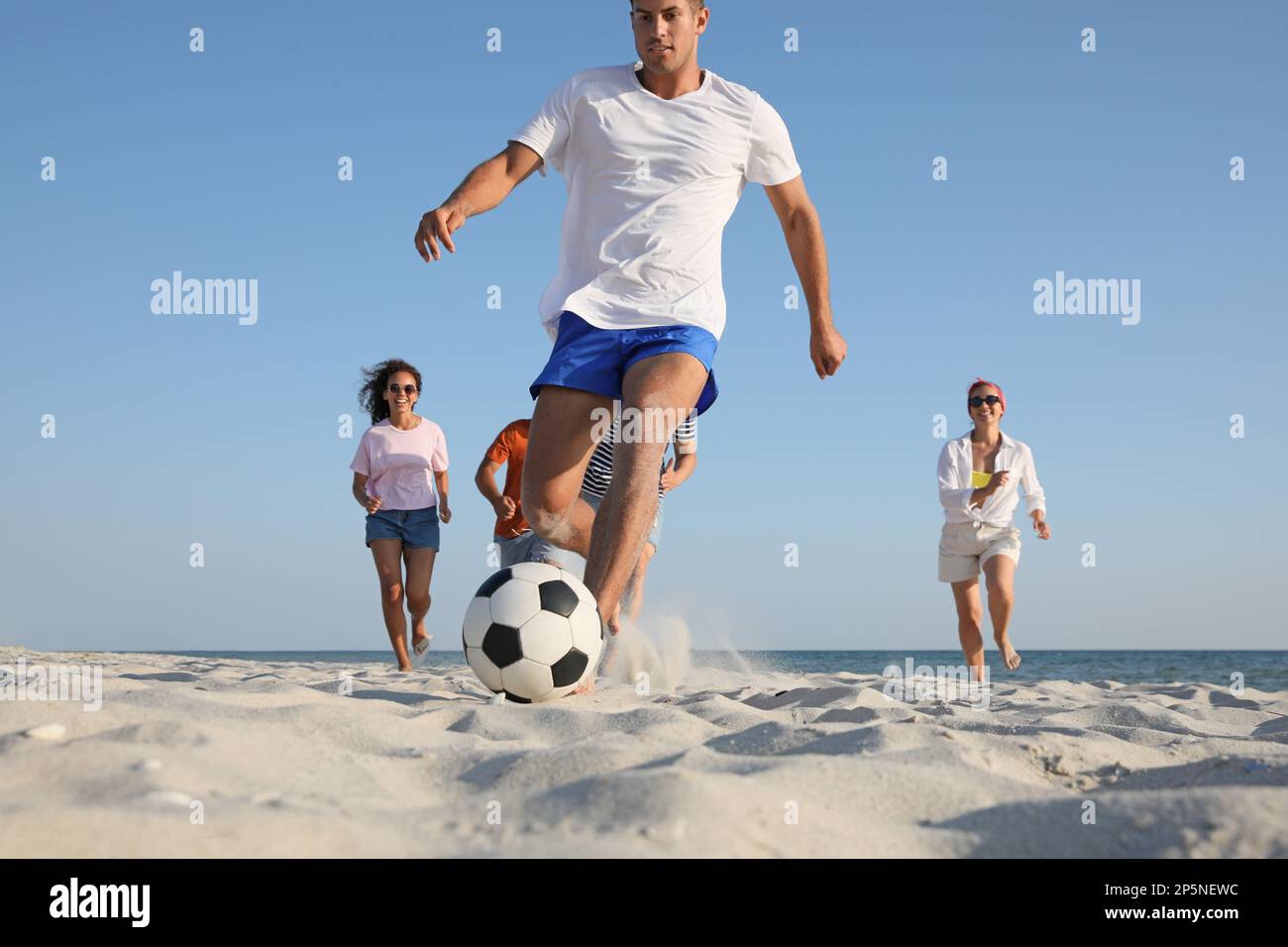 Group of friends playing football at beach, focus on ball Stock Photo ...