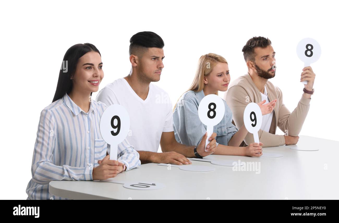 Panel of judges holding different score signs at table on white ...