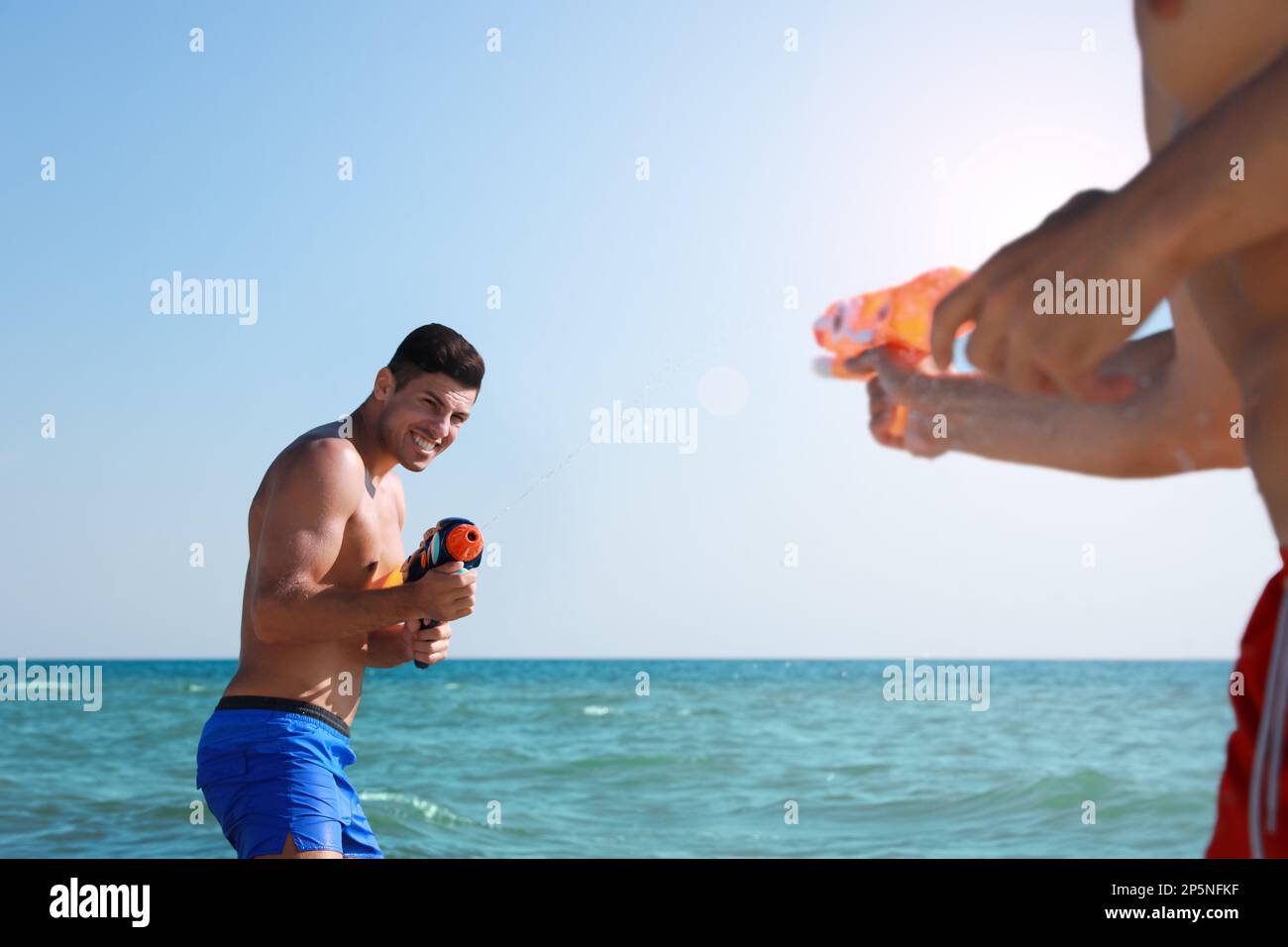 Friends with water guns having fun in sea Stock Photo - Alamy