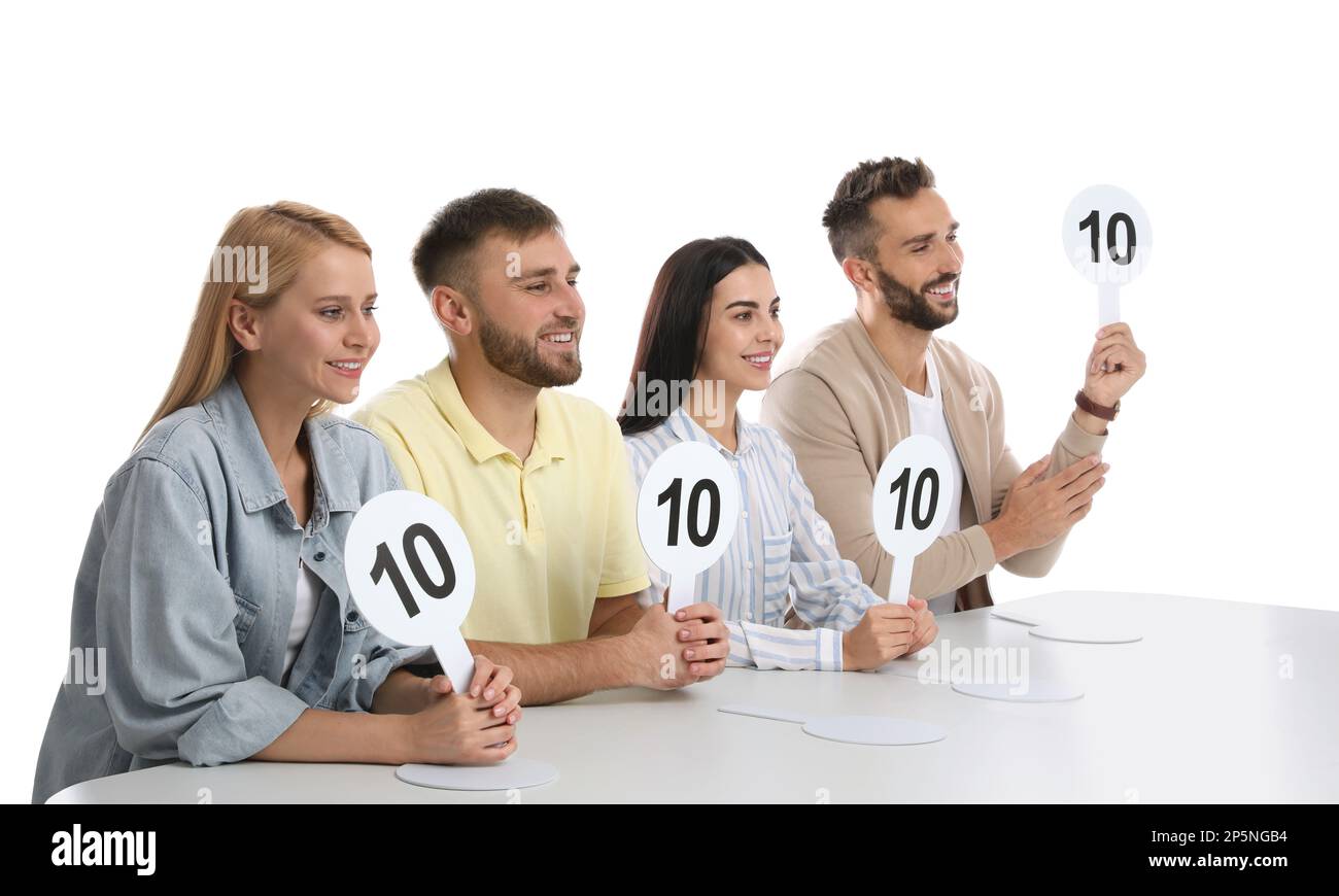 Panel of judges holding signs with highest score at table on white ...