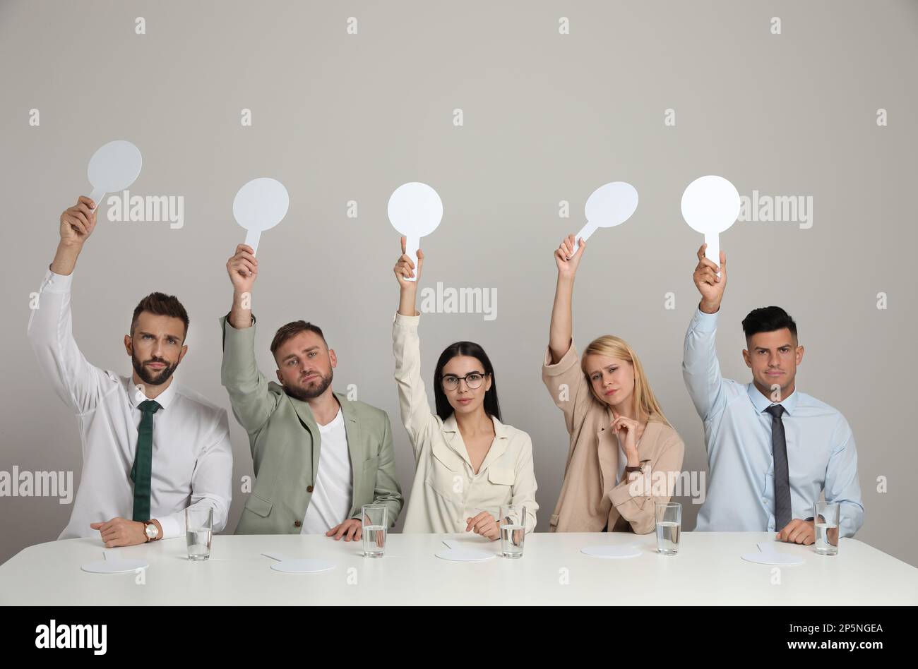 Panel of disappointed judges holding blank score signs at table on ...