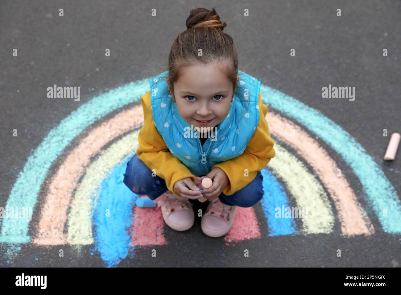 Happy child near chalk drawing of rainbow on asphalt, above view Stock ...