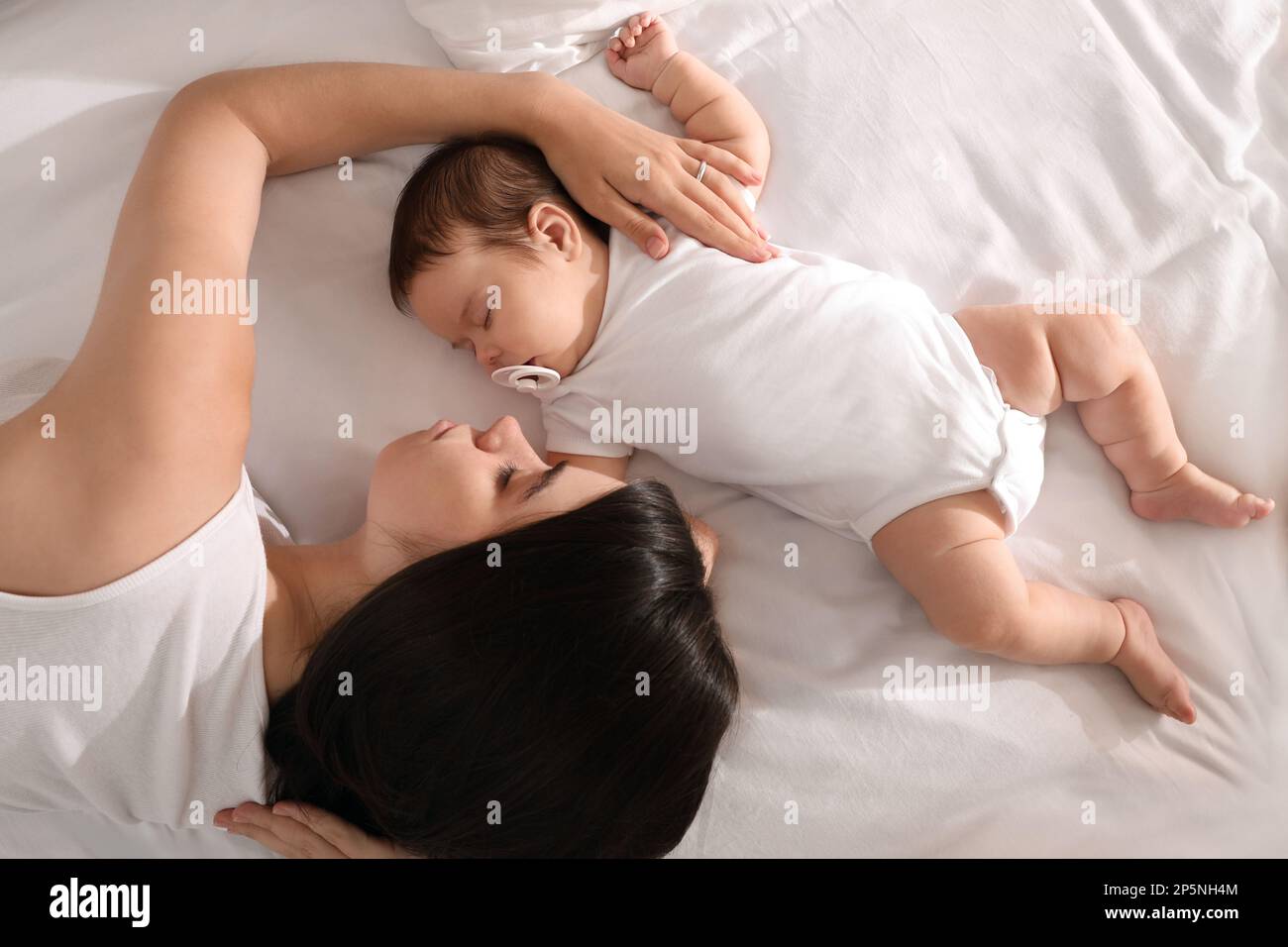 Young mother resting near her sleeping baby on bed, top view Stock ...