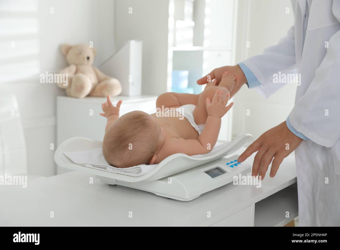 Pediatrician weighting cute baby in clinic, closeup. Health care Stock ...