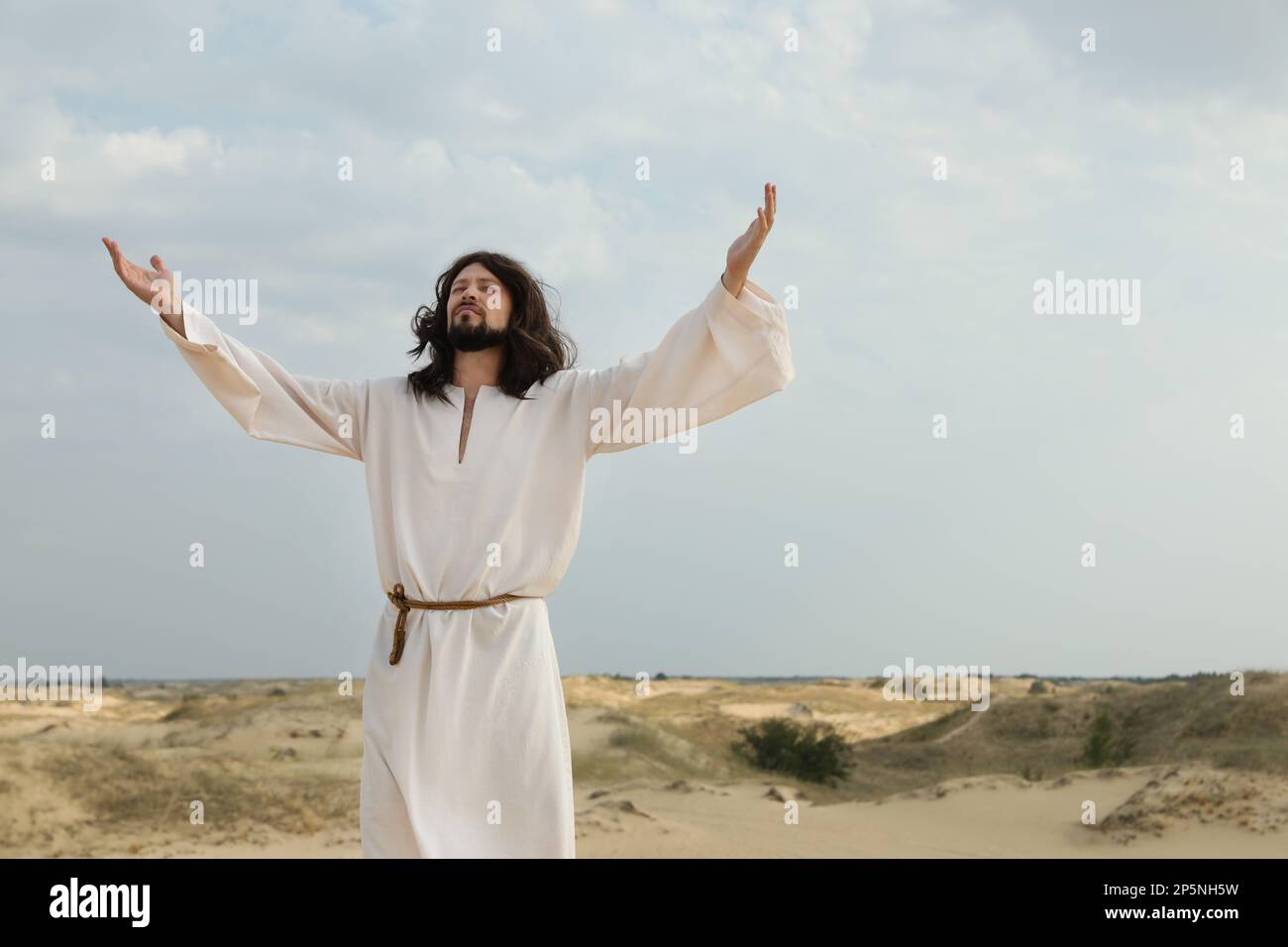 Jesus Christ raising hands in desert on sunny day Stock Photo - Alamy