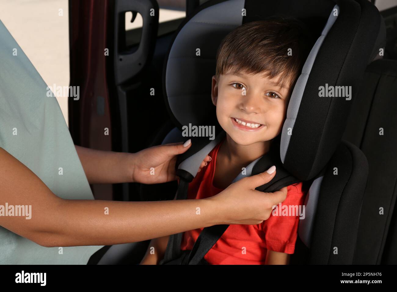 Mother fastening her son with car safety belt in child seat Stock Photo ...