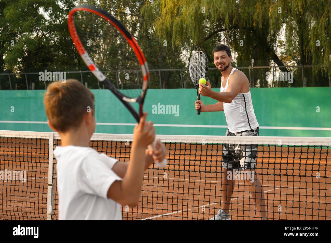 Father with his son playing tennis on court Stock Photo - Alamy